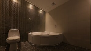 Um banheiro com vaso sanitário, banheira e paredes revestidas de azulejos.