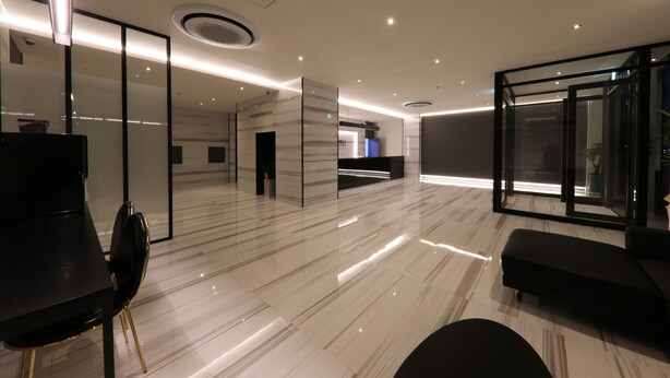Um hall de hotel moderno com design elegante, destacando um piso de mármore, móveis contemporâneos e grandes janelas com vista para o exterior.
