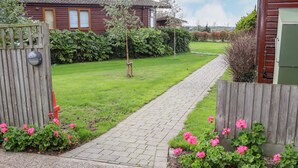 Uma trilha que leva a uma casa de madeira com jardim.