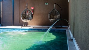 Piscina com duas cadeiras de balanço e um extintor na parede.