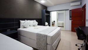 Quarto de hotel moderno com uma cama grande, mesas de cabeceira, uma escrivaninha e um guarda-roupa.