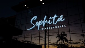 Exterior do Hotel Sophita Business com uma grande placa iluminada.