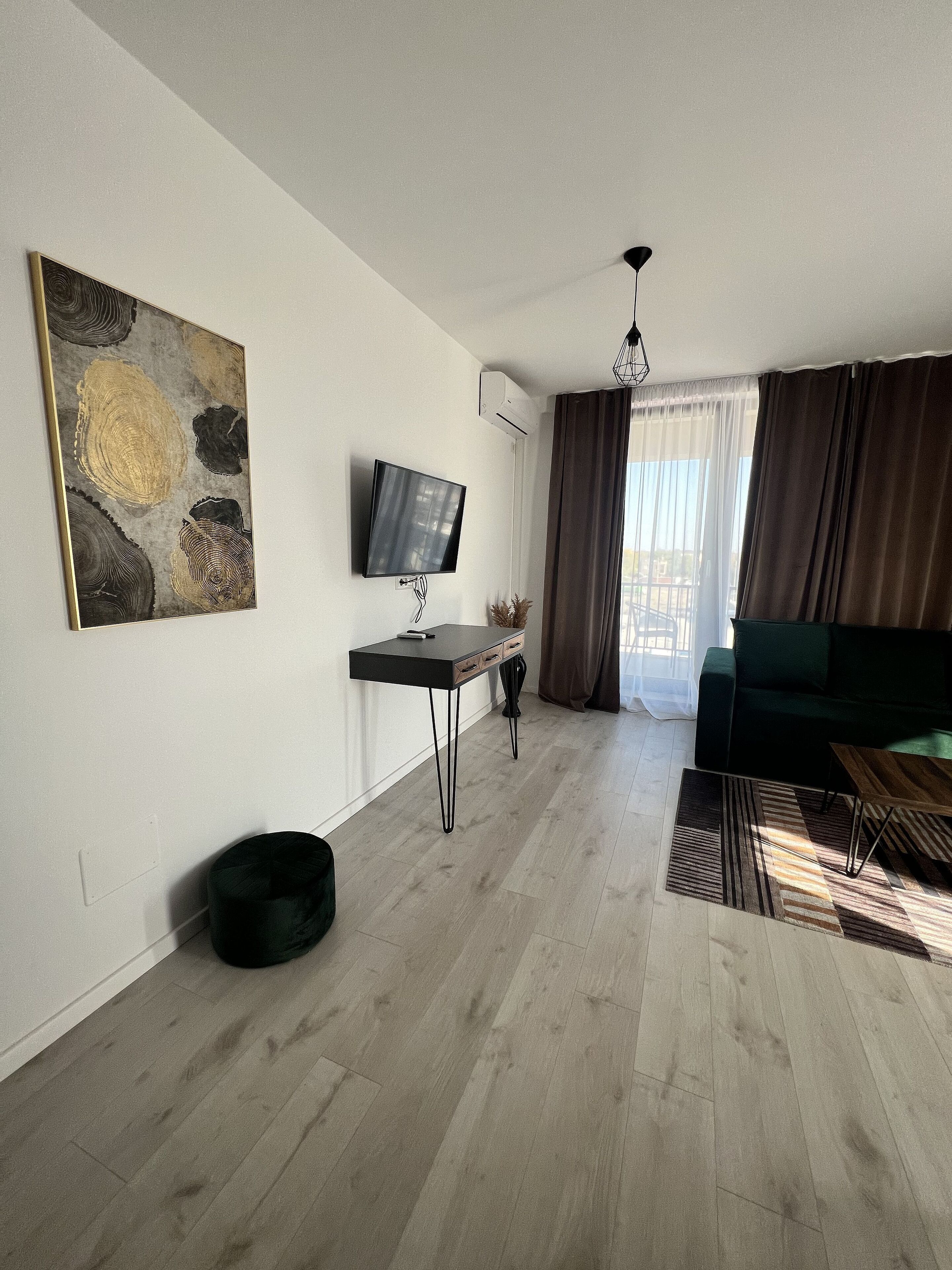 Uma sala de estar moderna com uma TV de tela plana, um sofá preto e um grande quadro abstrato na parede.