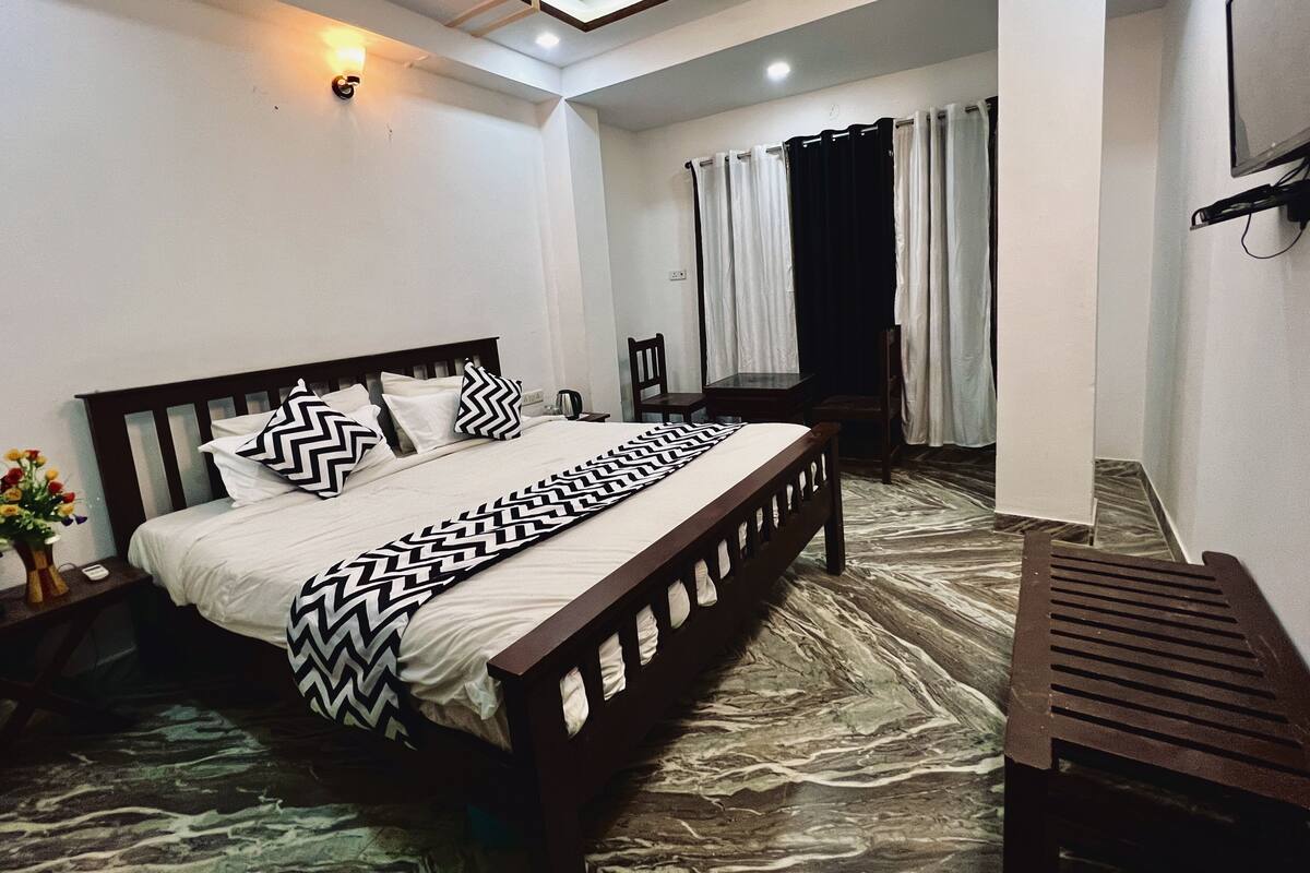 Quarto com cama, mesa de cabeceira e pequena mesa com cadeiras.