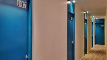 Um corredor com portas azuis, numeradas 107, e soalho de madeira.