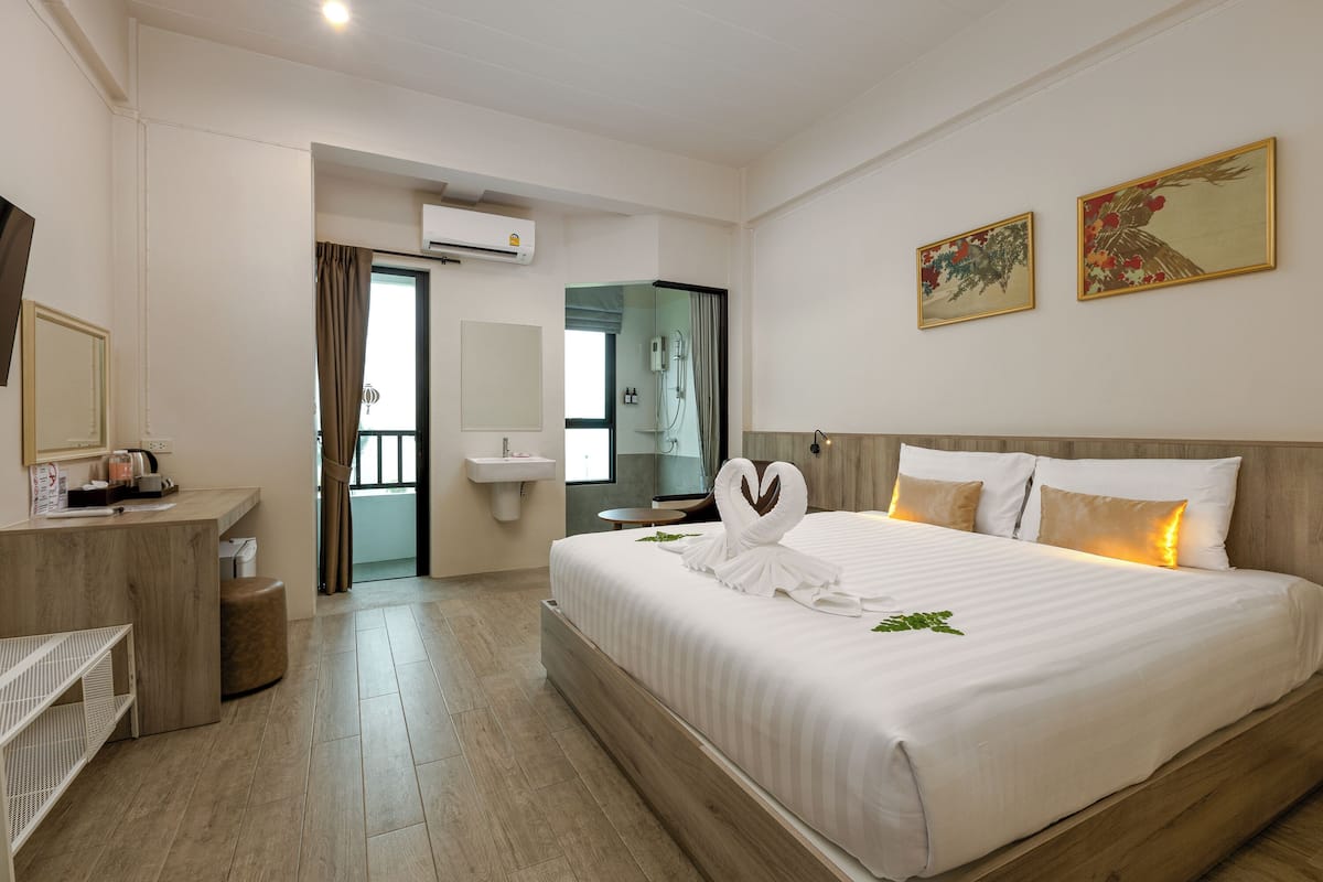 Quarto de hotel com uma cama grande, uma mesa de trabalho, banheiro e vista para o exterior.