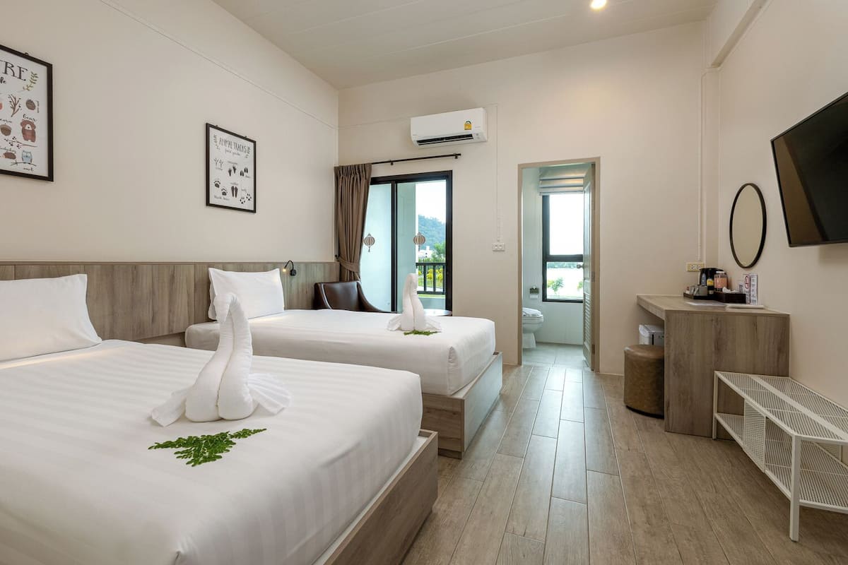 Quarto de hotel com duas camas, uma escrivaninha, televisão e varanda.