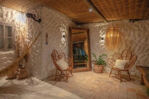 Quarto com design rústico, com cadeiras de fibra, um espelho grande e um ventilador de teto.