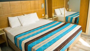 Quarto de hotel com cama grande, cabeceira de madeira e um espelho refletindo o quarto.