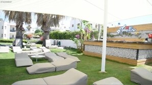 Uma área de estar coberta ao ar livre com cadeiras de lounge e um bar.