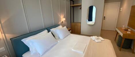 Quarto de hotel com uma cama grande, uma mesa de cabeceira, um espelho e um guarda-roupa.