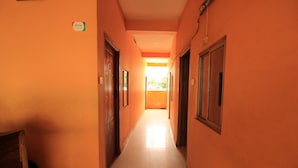 Um corredor com paredes e portas laranja, que leva a uma área iluminada com luz natural.