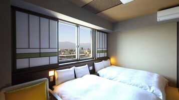 Quarto de hotel com duas camas, vista para a cidade através de amplas janelas e um painel de parede de estilo tradicional.