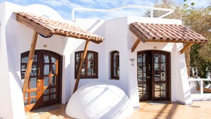 Um edifício branco com telhado ladrilhado, portas de madeira e uma grande estrutura em cúpula branca.