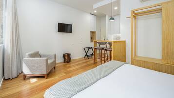 Um quarto moderno com uma cama, uma cadeira, uma escrivaninha e uma televisão na parede.