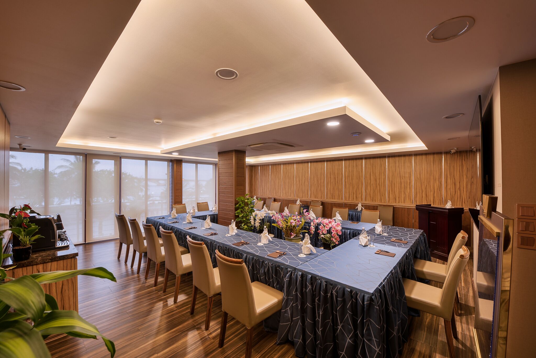 Uma área de jantar moderna com uma mesa comprida, cadeiras e uma parede de painéis de madeira.