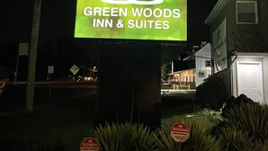 Placa noturna do Green Woods Inn & Suites com silhuetas de cisnes e texto.