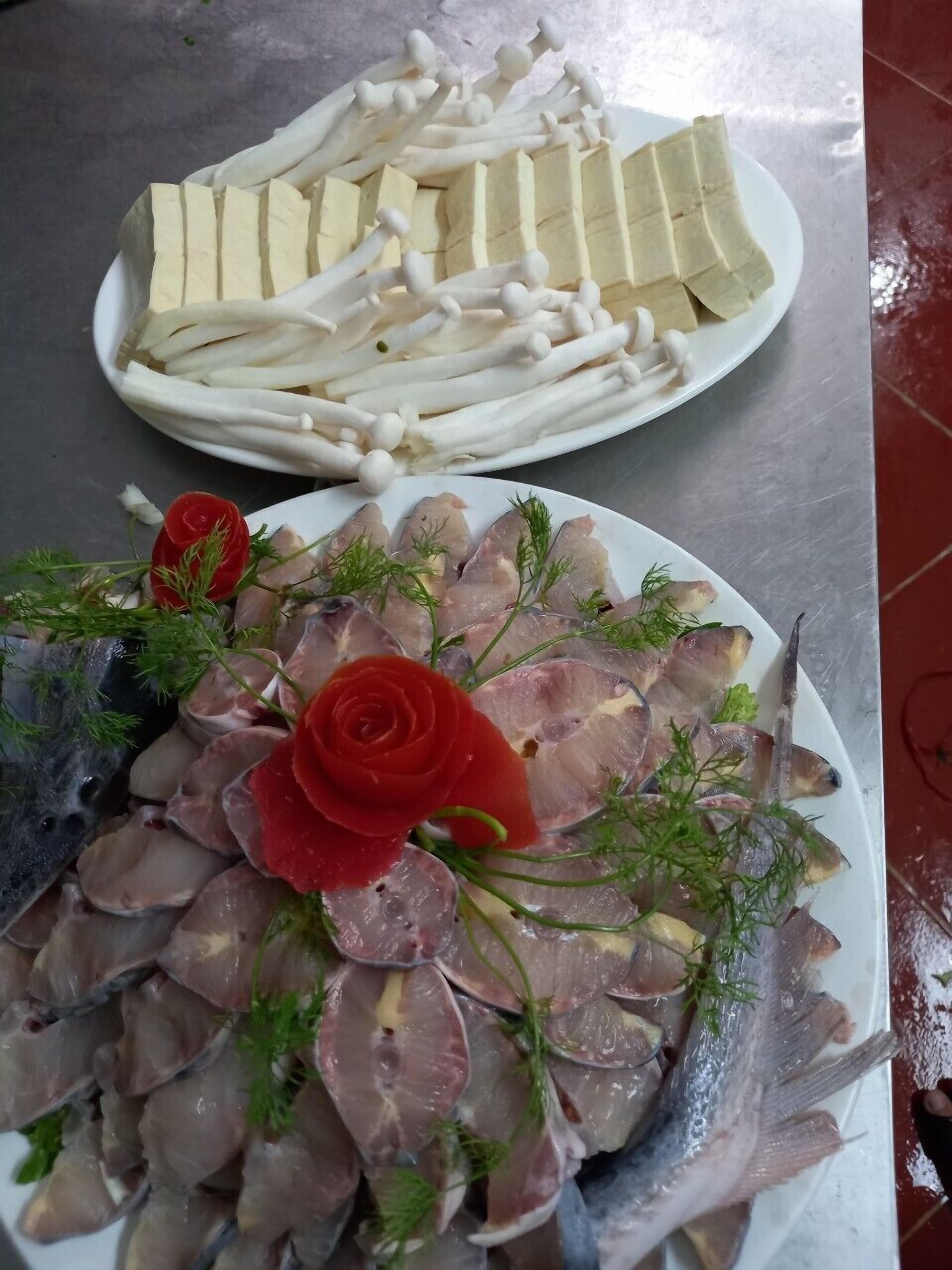 Um prato de cogumelos fatiados e um prato de peixe decorado com ervas e uma rosa vermelha.