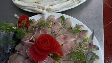 Um prato de cogumelos fatiados e um prato de peixe decorado com ervas e uma rosa vermelha.