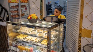 Vitrine de uma padaria com diversos produtos de panificação e uma cesta de frutas.
