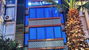 Um hotel chamado "MIRA KUKUYALI HOTEL", com design moderno, com vários andares, grandes janelas e áreas de estar ao ar livre.