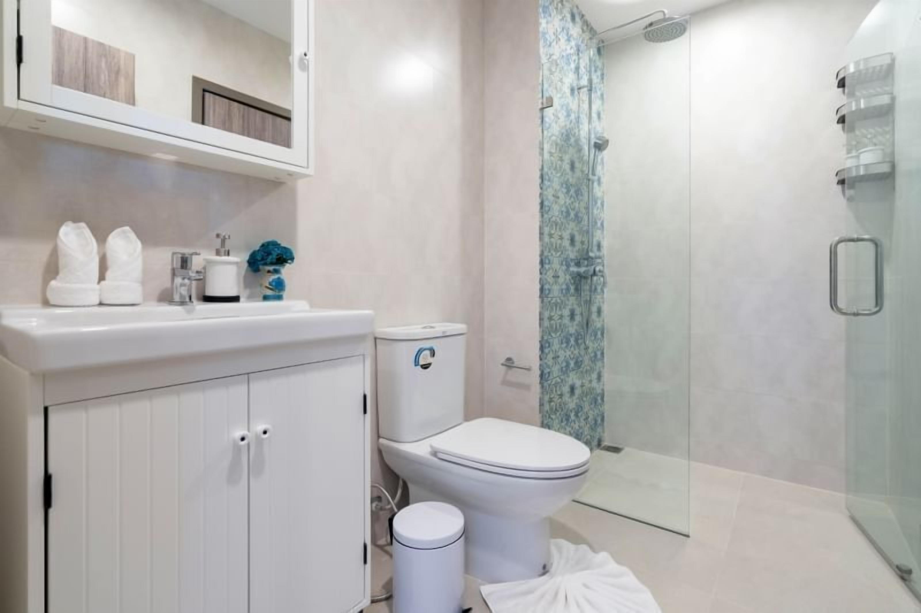 Uma casa de banho moderna com sanita, lavatório e chuveiro.