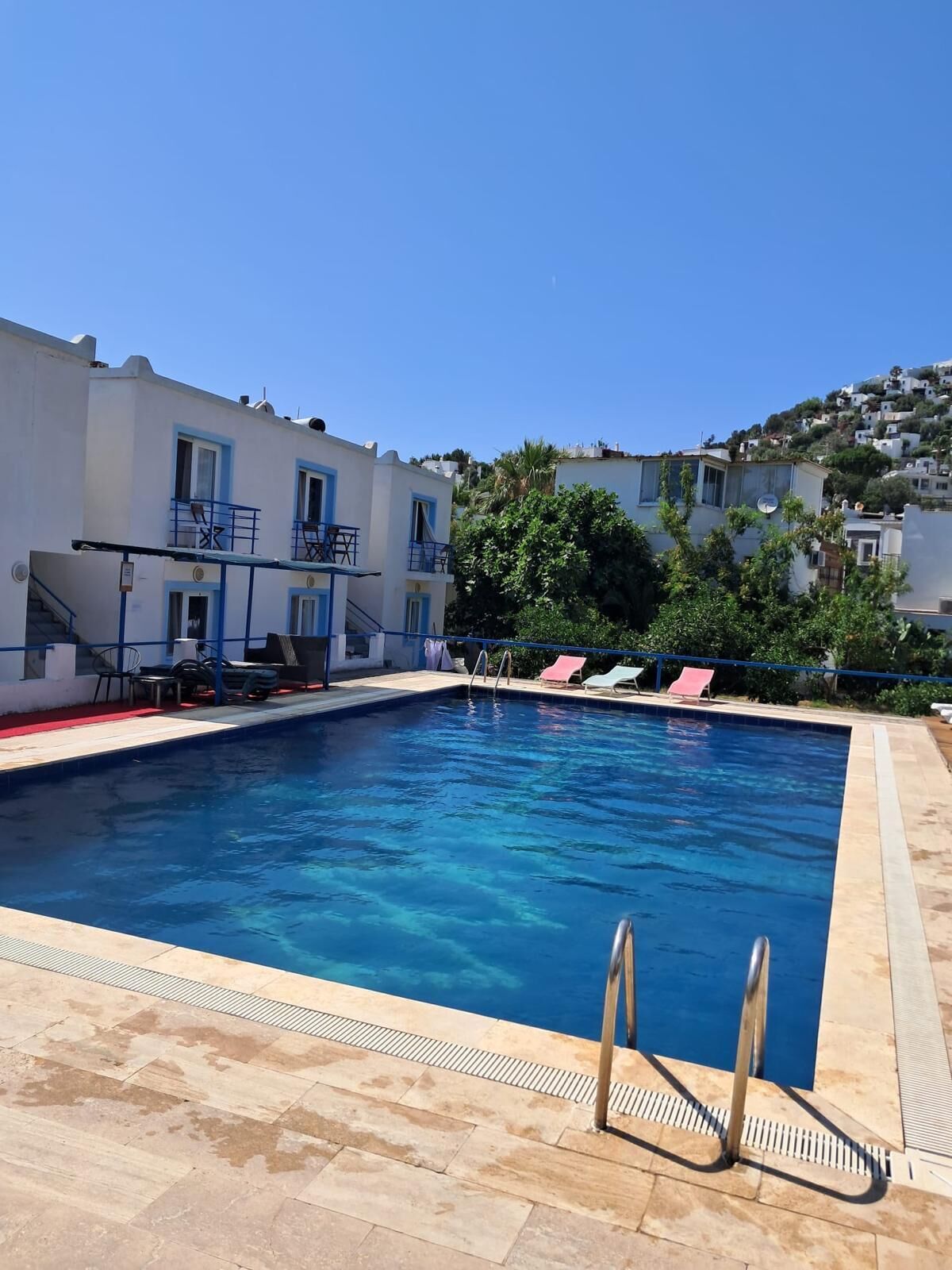 Piscina com água azul cristalina, rodeada por um deck revestido com azulejos.