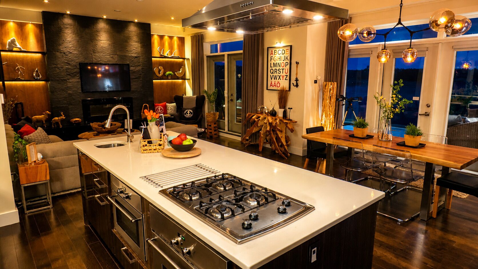 Uma cozinha moderna com uma ilha central, uma sala de jantar com mesa de madeira e uma sala de estar com sofá e televisão.