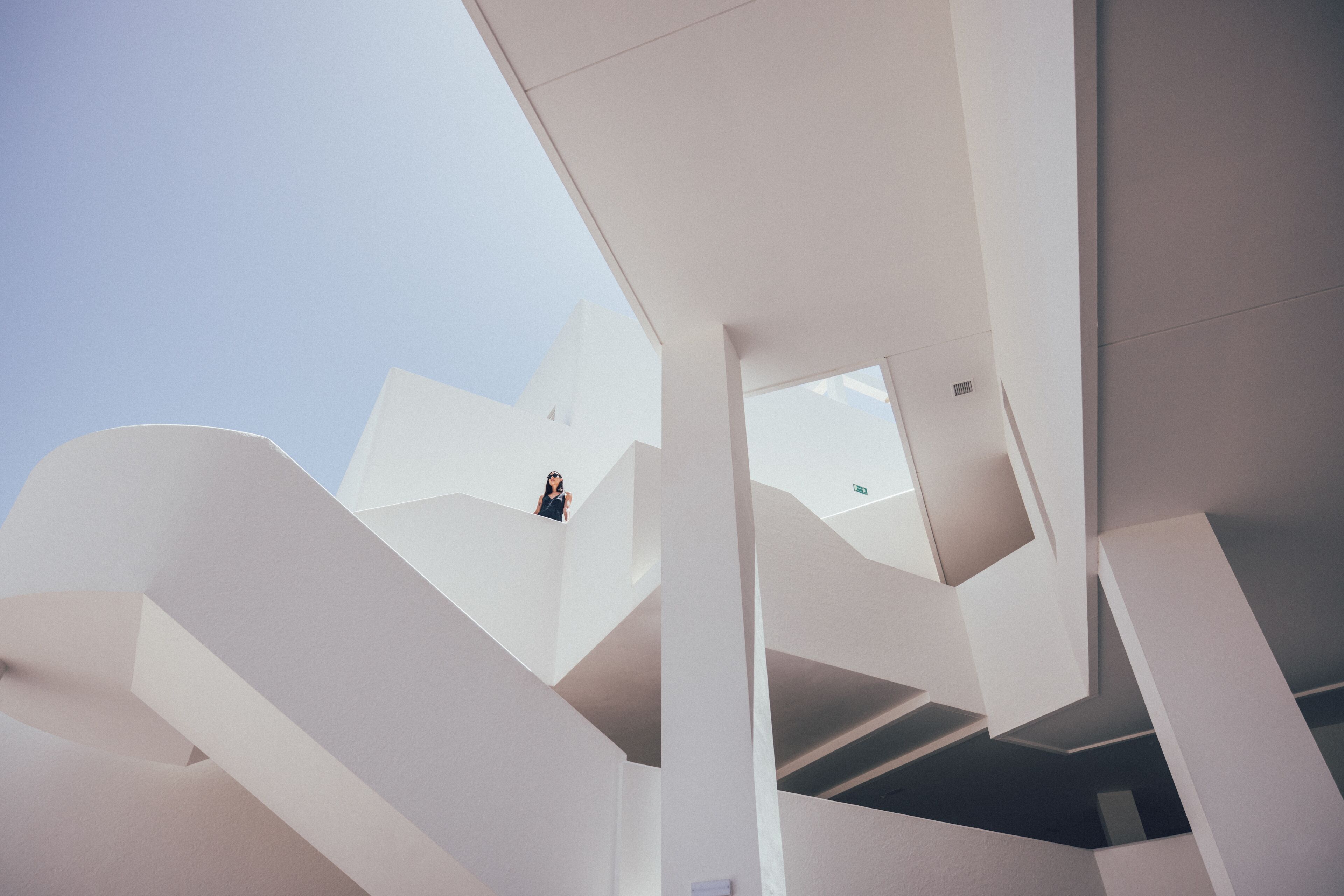 Uma estrutura arquitetônica moderna com formas geométricas brancas e um céu claro ao fundo.