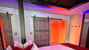 Quarto com teto estrelado, guarda-roupa de madeira e porta deslizante iluminada por luz laranja.