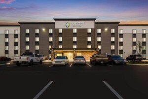 Hotel com fachada moderna, vários espaços de estacionamento e céu claro.