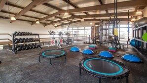 Uma academia com trampolins, halteres e equipamentos de ginástica.