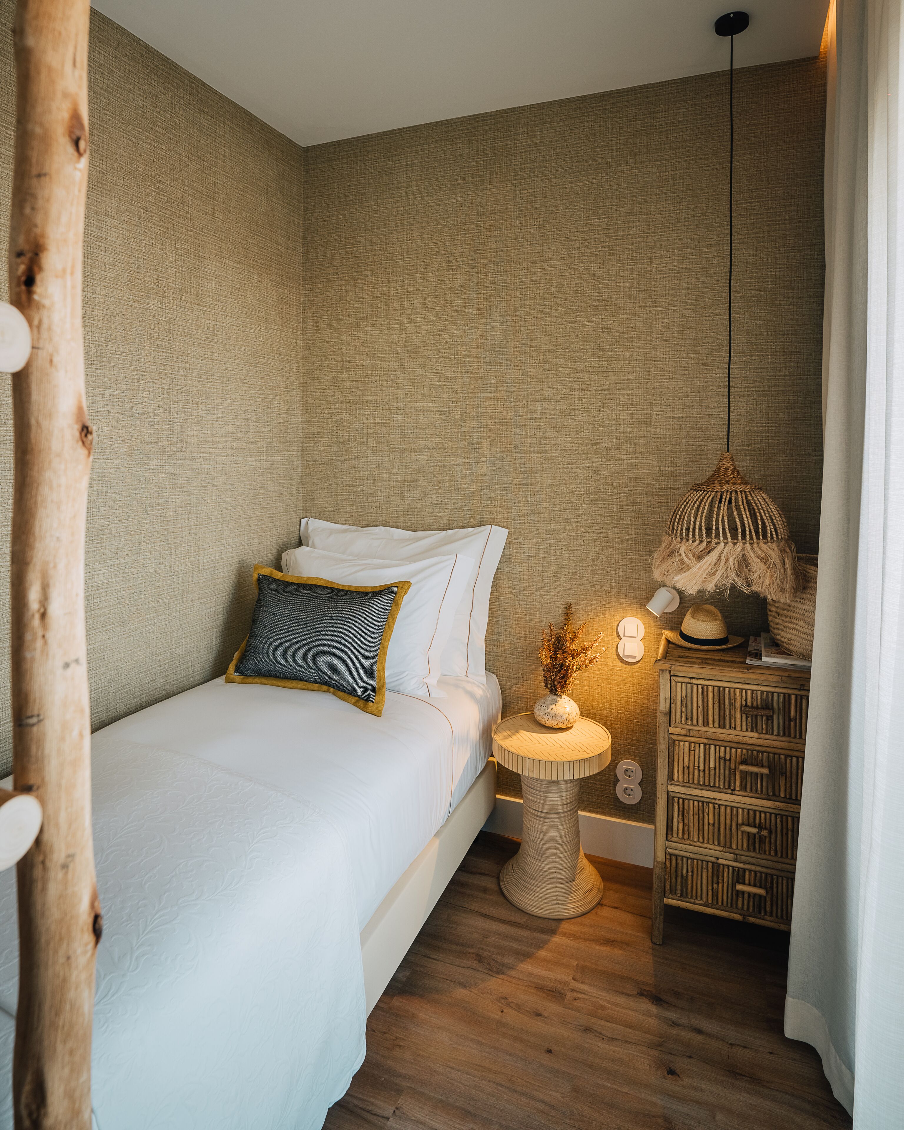Quarto com cama, mesa de cabeceira, abajur e parede com textura.