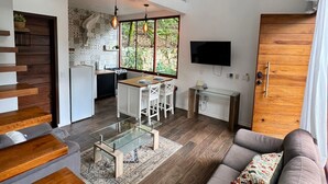 Um espaço de estar moderno com escada, área de refeições, cozinha e sala de estar com sofá e televisão.