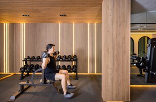 Uma academia com parede de madeira, equipamentos de exercício e halteres.