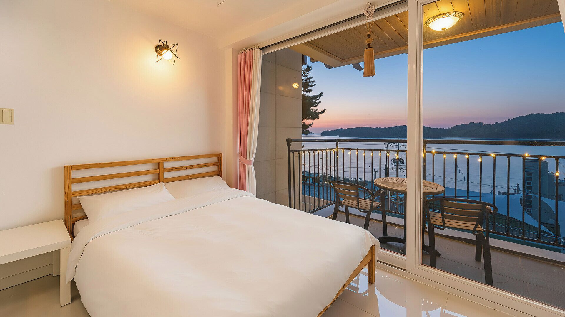 Quarto com cama, um banquinho e varanda com mesa e cadeiras.