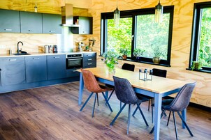 Cozinha moderna com armários cinza, bancada de madeira e área de refeições com mesa e cadeiras de madeira.