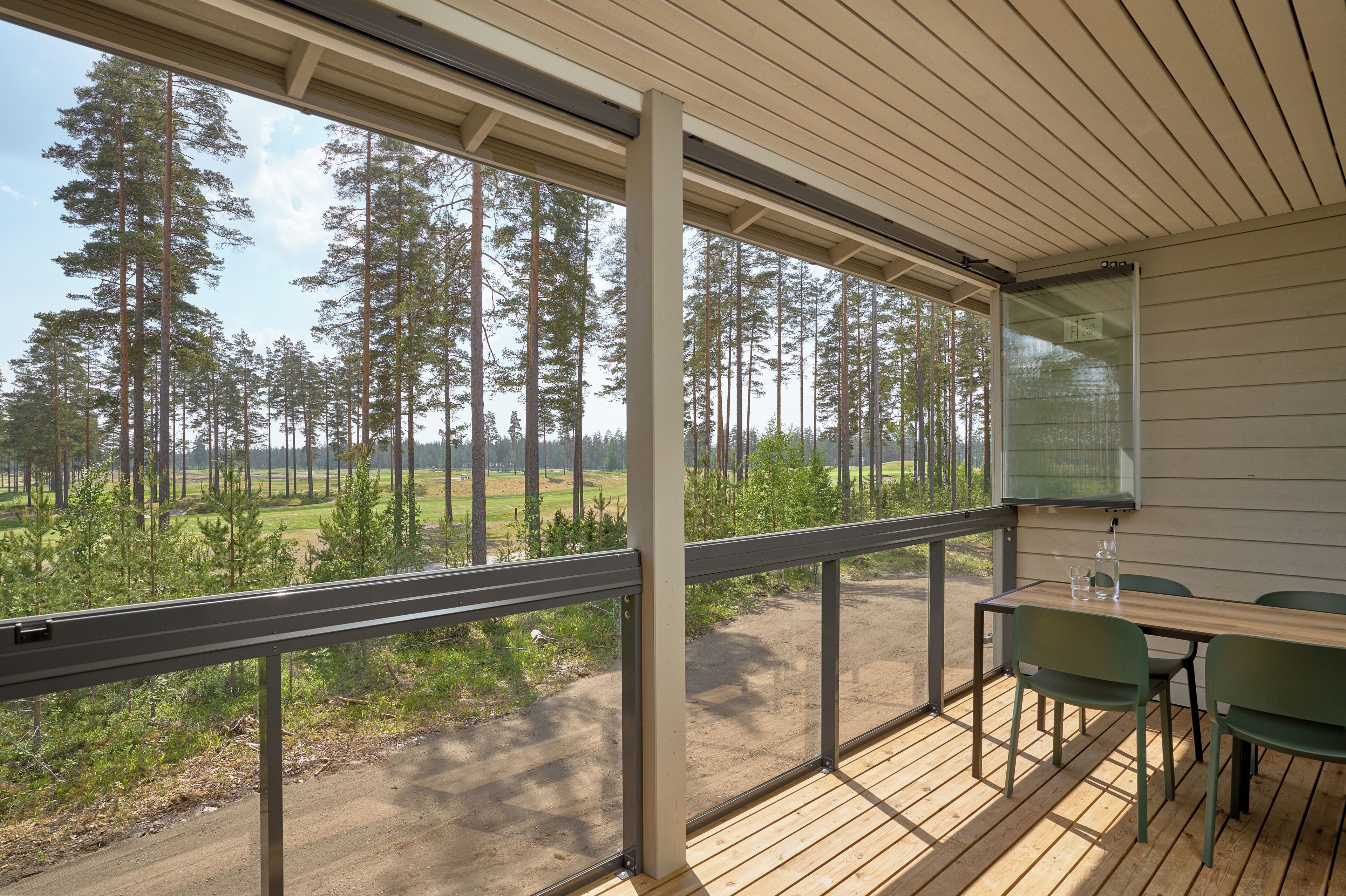 Área externa coberta com mesa e cadeiras, com vista para uma paisagem arborizada.