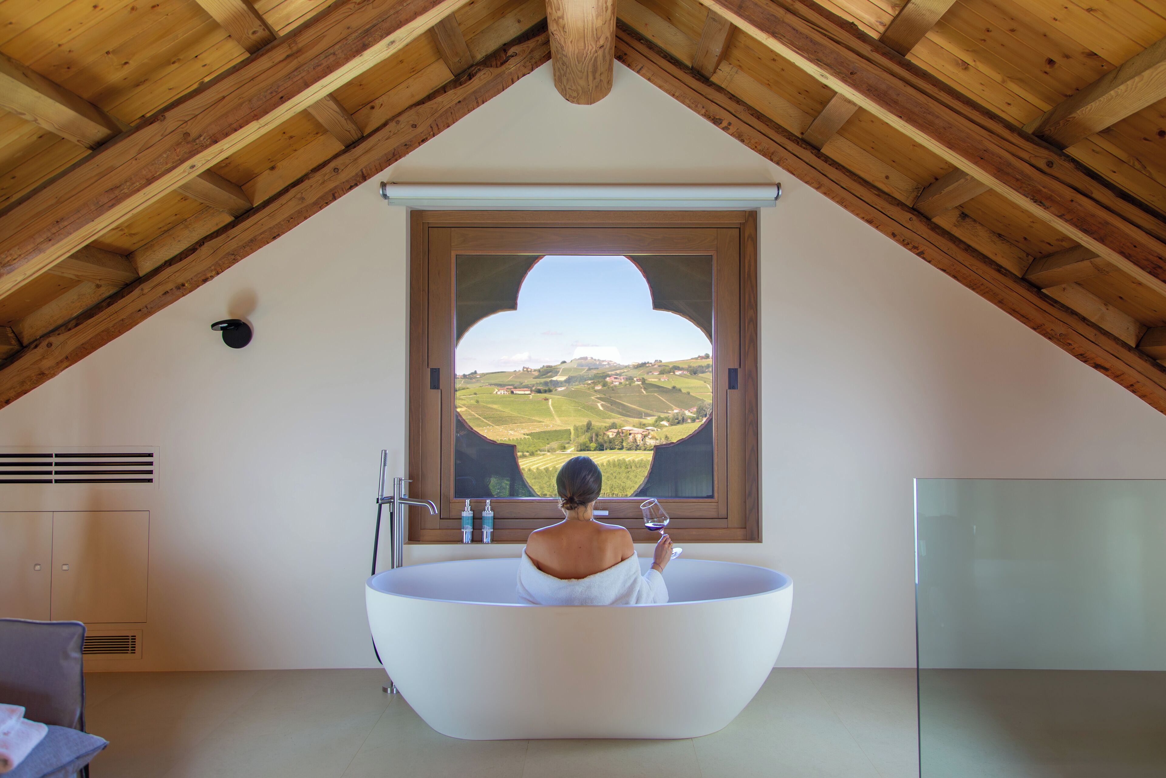 Mulher relaxando em banheira com vista para a paisagem através da janela.
