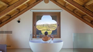 Mulher relaxando em banheira com vista para a paisagem através da janela.