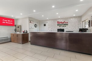 Uma área de recepção com tela digital anunciando Wi-Fi gratuito, um relógio e a placa Red Roof Inn.
