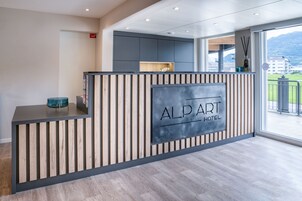 Uma receção com design moderno, exibindo o letreiro "ALP ART HOTEL".
