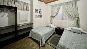 Quarto com duas camas, teto de madeira, janela com cortinas, um espelho e uma pequena prateleira com um espelho e alguns objetos.