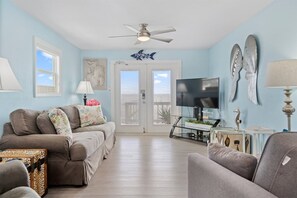 Sala de estar com sofá, mesa de centro, televisão e objetos decorativos.