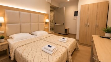 Quarto de hotel com uma cama grande, mesas de cabeceira, um guarda-roupa e um banheiro.