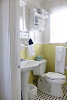 Um banheiro com pia branca, vaso sanitário e porta-toalhas com toalhas dobradas.
