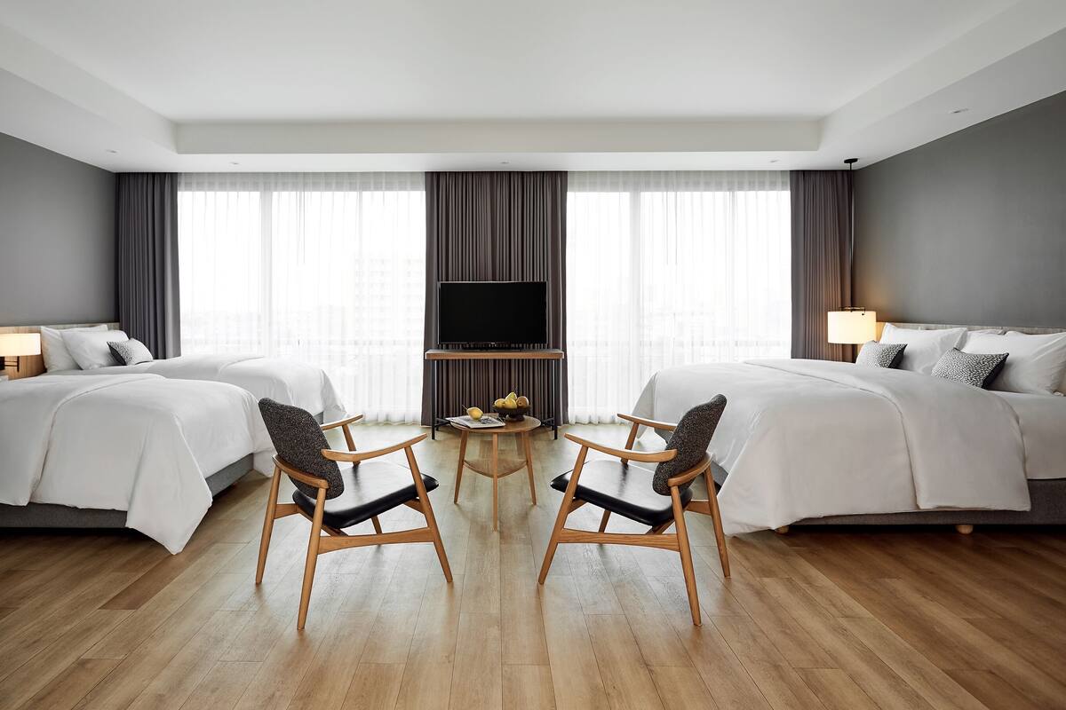 Quarto de hotel com duas camas, uma televisão e uma mesa de jantar com cadeiras.