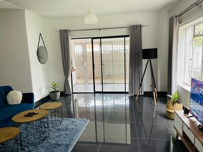 Uma sala de estar moderna com um sofá azul, uma mesa de centro, uma televisão e uma varanda com vista.