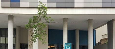 Um edifício moderno com fachada quadriculada, grandes colunas e uma placa indicando uma área de estacionamento.