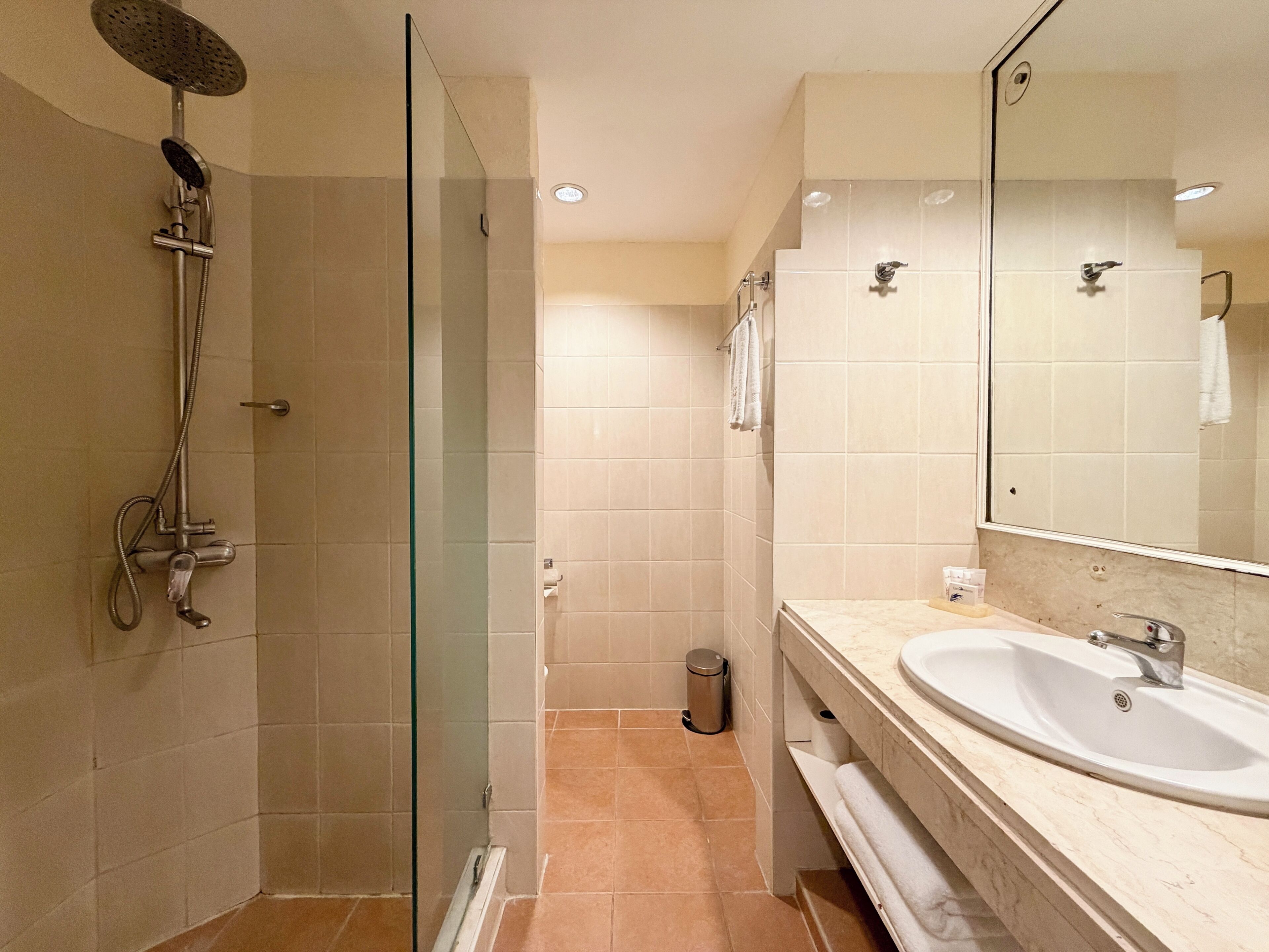 Uma casa de banho moderna com chuveiro de vidro, um espelho grande e lavatório de mármore.